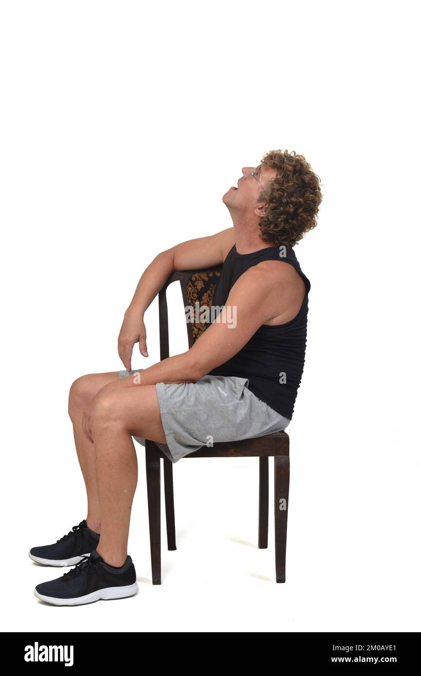 side view of a man with sportswear sitting on chair looking up on white ...
