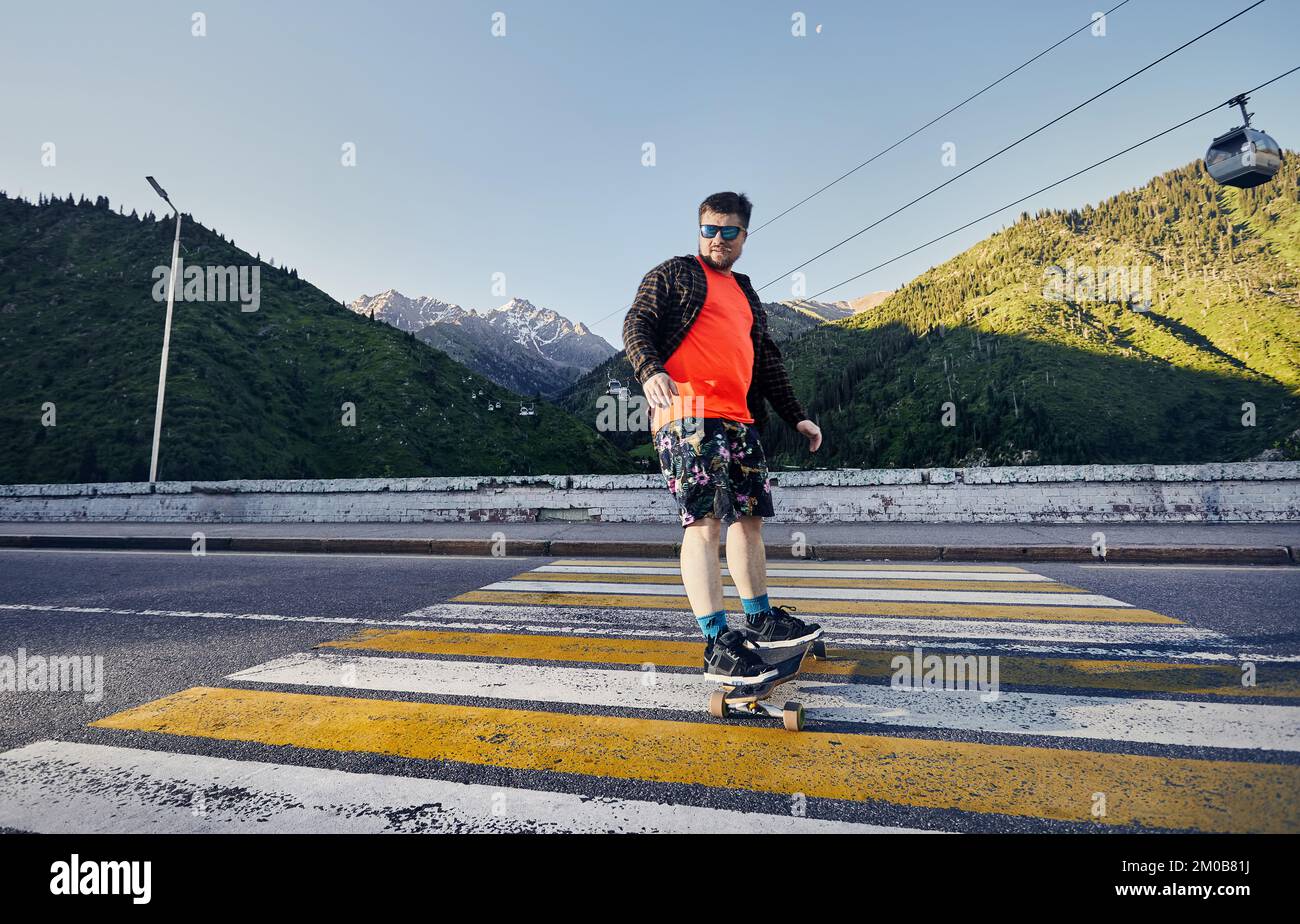 Bearded man Skater ride in the mountain road on his longboard in Medeo ...