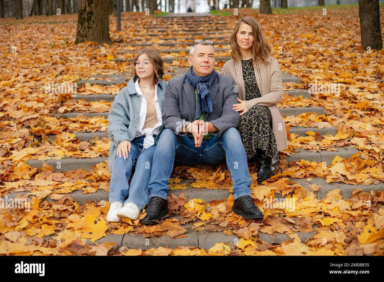 Portrait of family sitting on concrete stairs covered with yellow ...