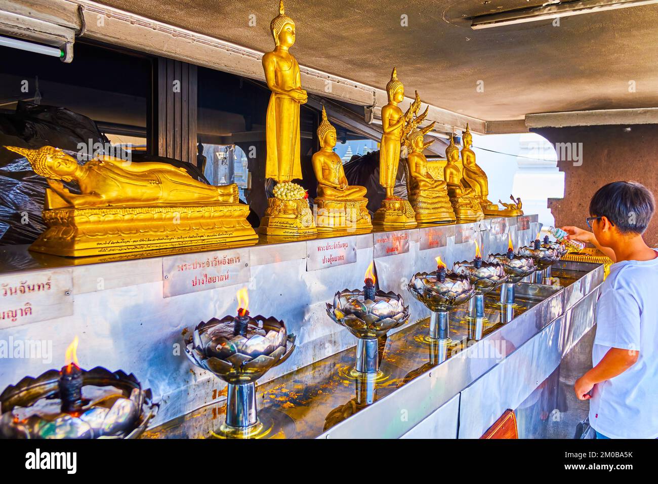 The young devotee making ritual pouring oil into oil lamps in small ...
