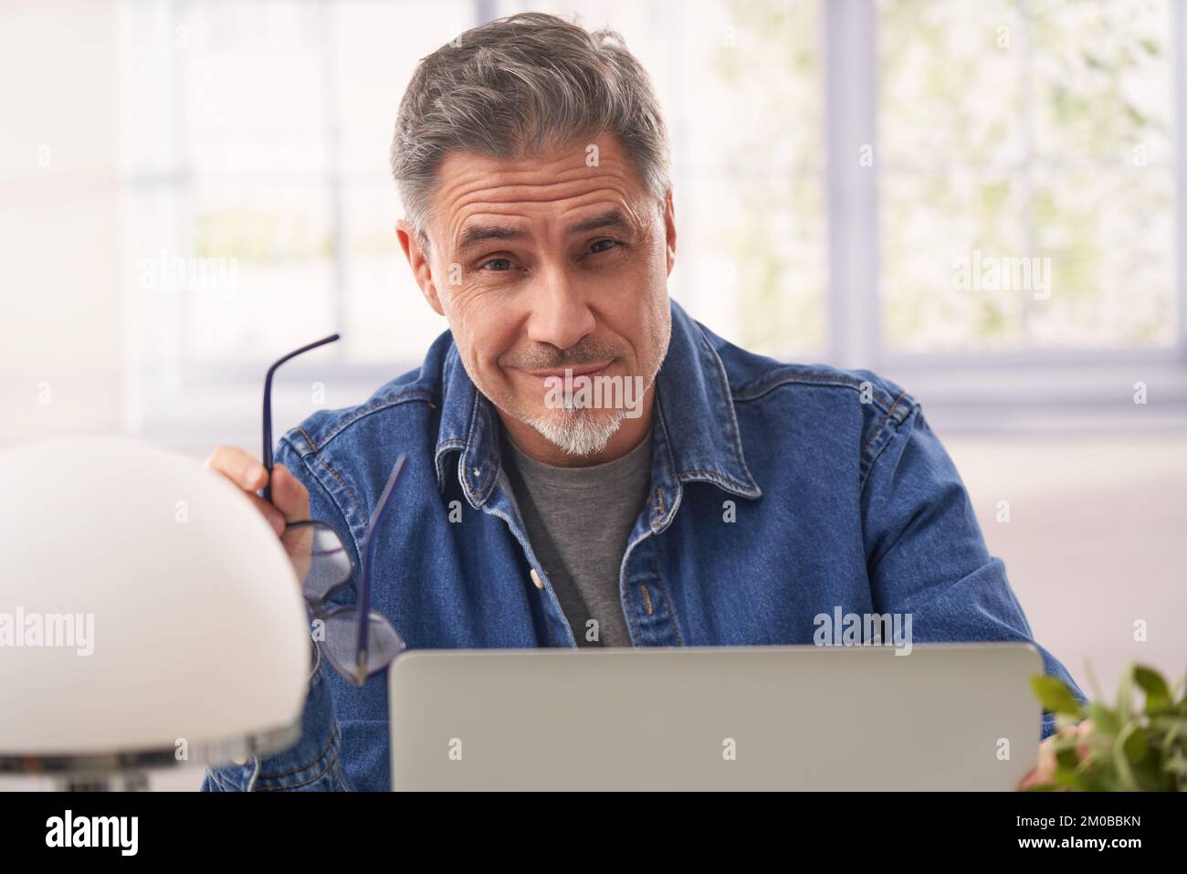 Happy mid adult man working with laptop computer at home, sitting at ...