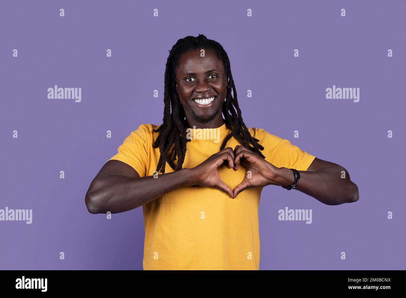 Playful african american man showing heart shaped symbol over chest ...