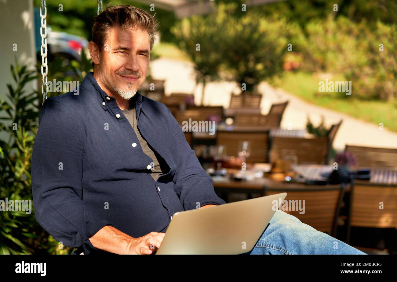 Outdoor portrait of mid adult man in 50s, happy confident smile ...