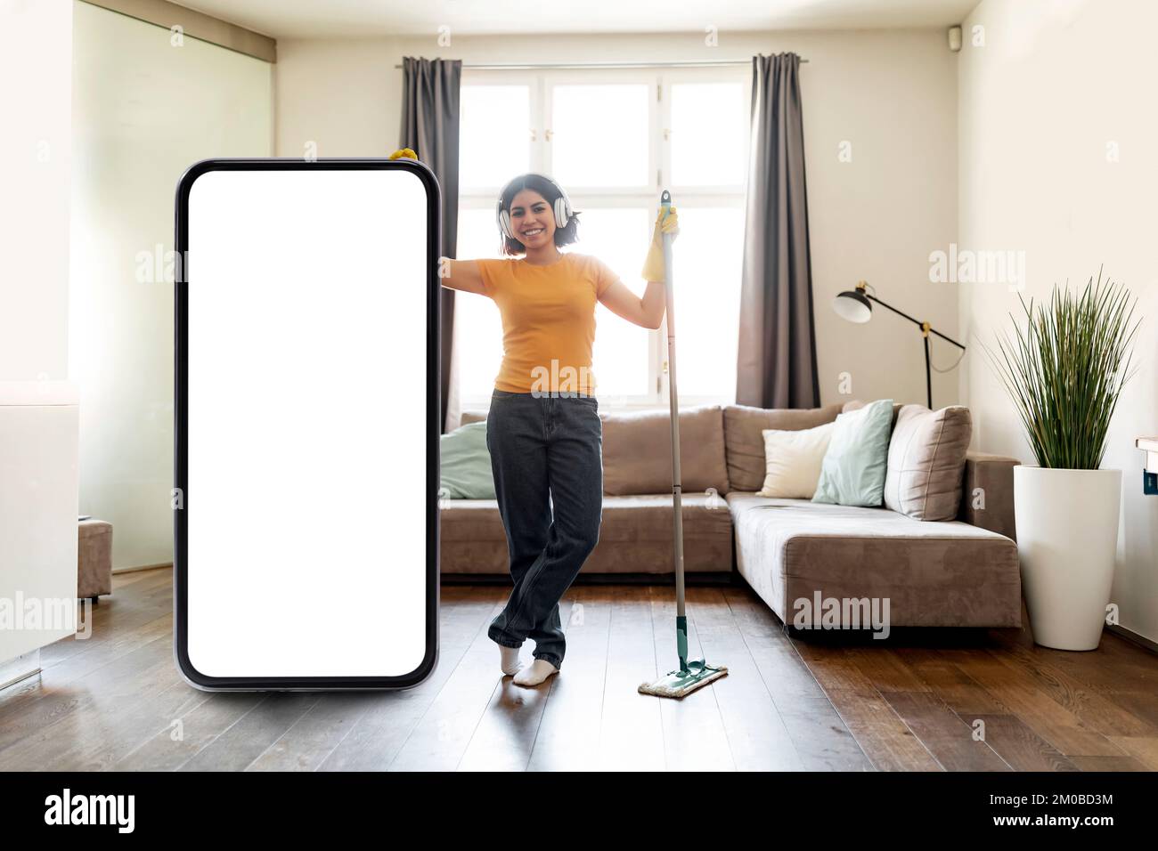 Young Arab Woman Cleaning Home And Standing Near Big Blank Smartphone ...