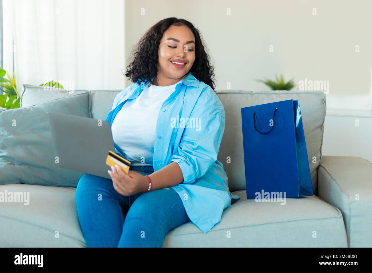 Happy black plus size woman with laptop pc and credit card sitting on ...