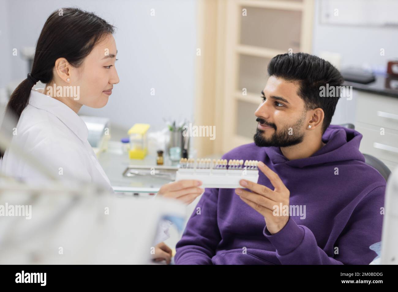 Tooth teeth tone palette. Beautiful asian female stomatologist orthodontist dentist choosing ...