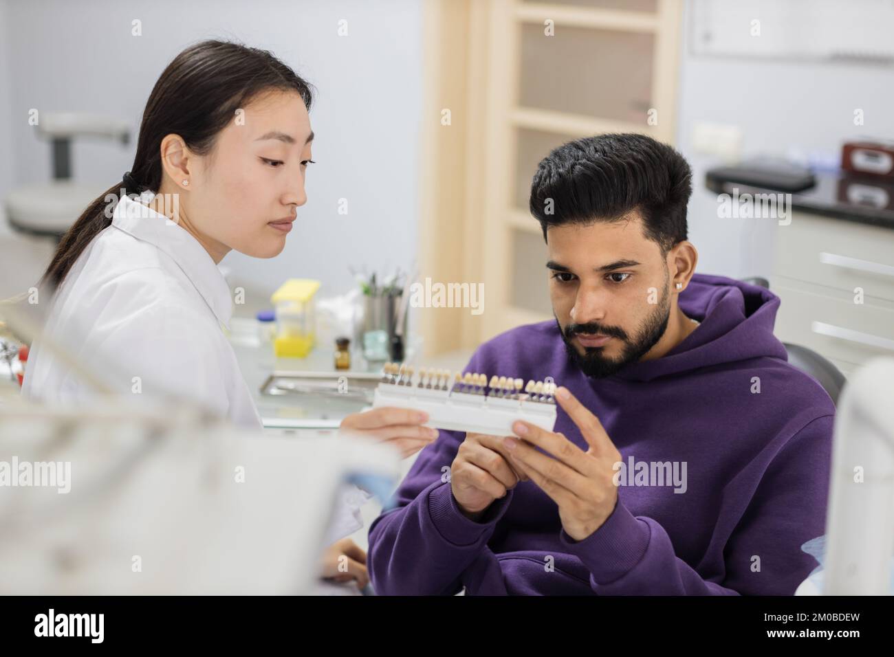 Tooth teeth tone palette. Beautiful asian female stomatologist orthodontist dentist choosing ...