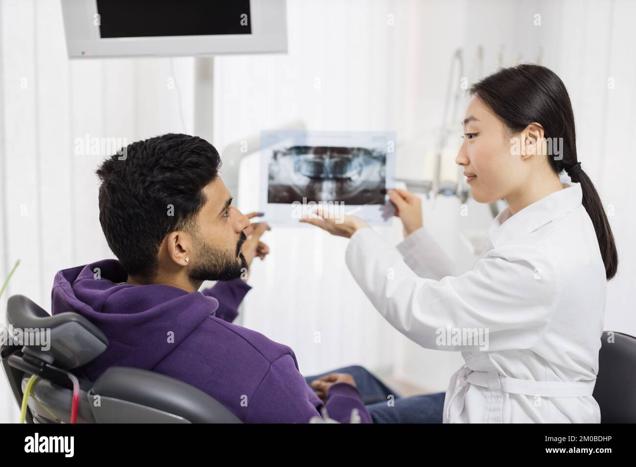 Back view of young attractive man visiting dentist, sitting in dental ...