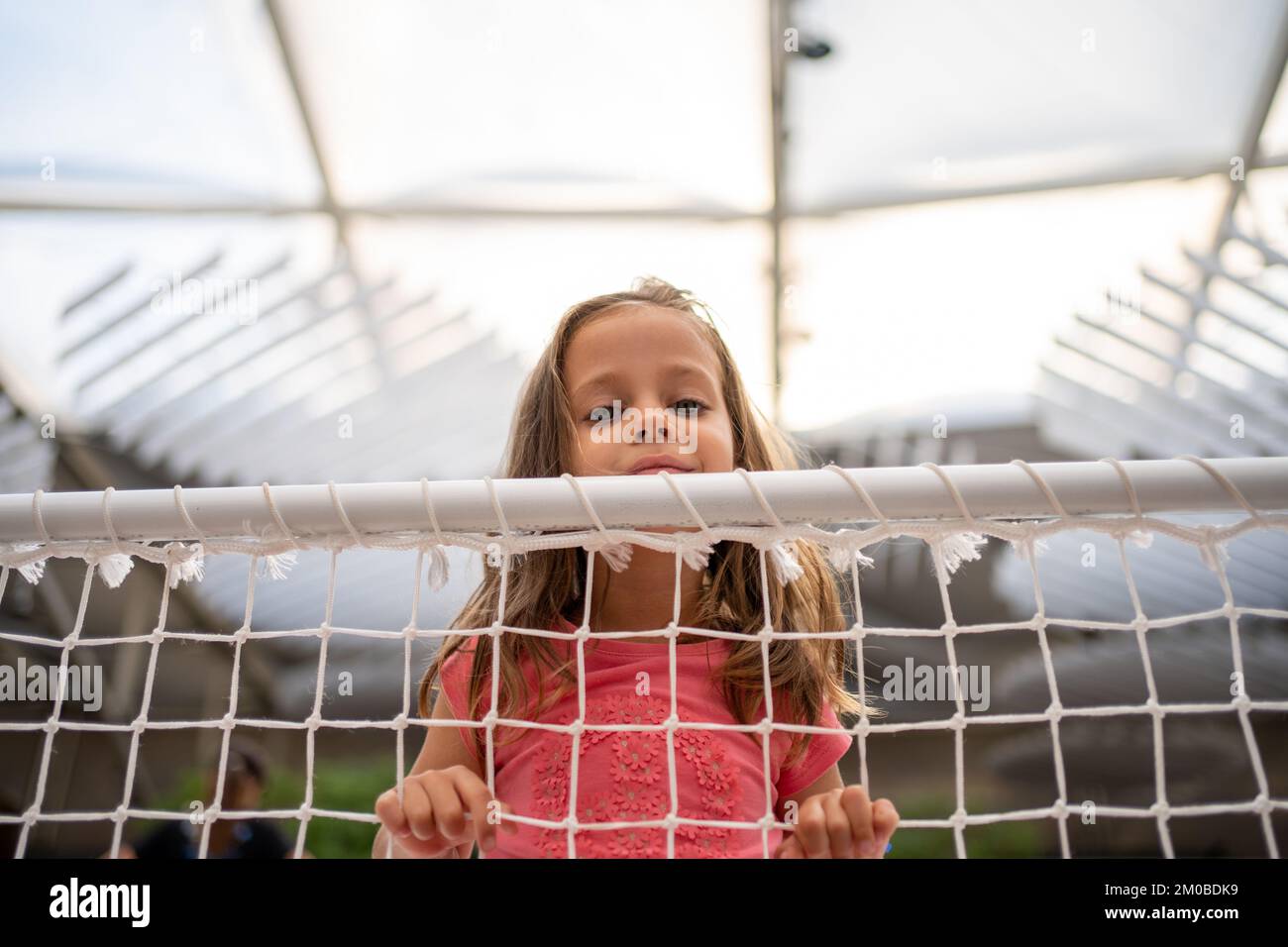 Little girl lean on net looking away with sad face emotion. Lost ...