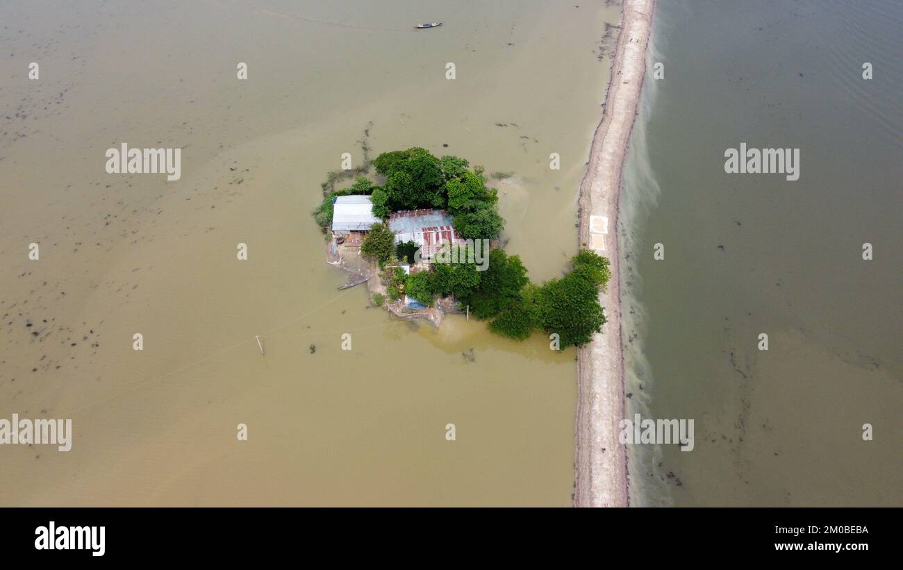 A high angle of buildings surrounded by lush trees and mud flats at a ...