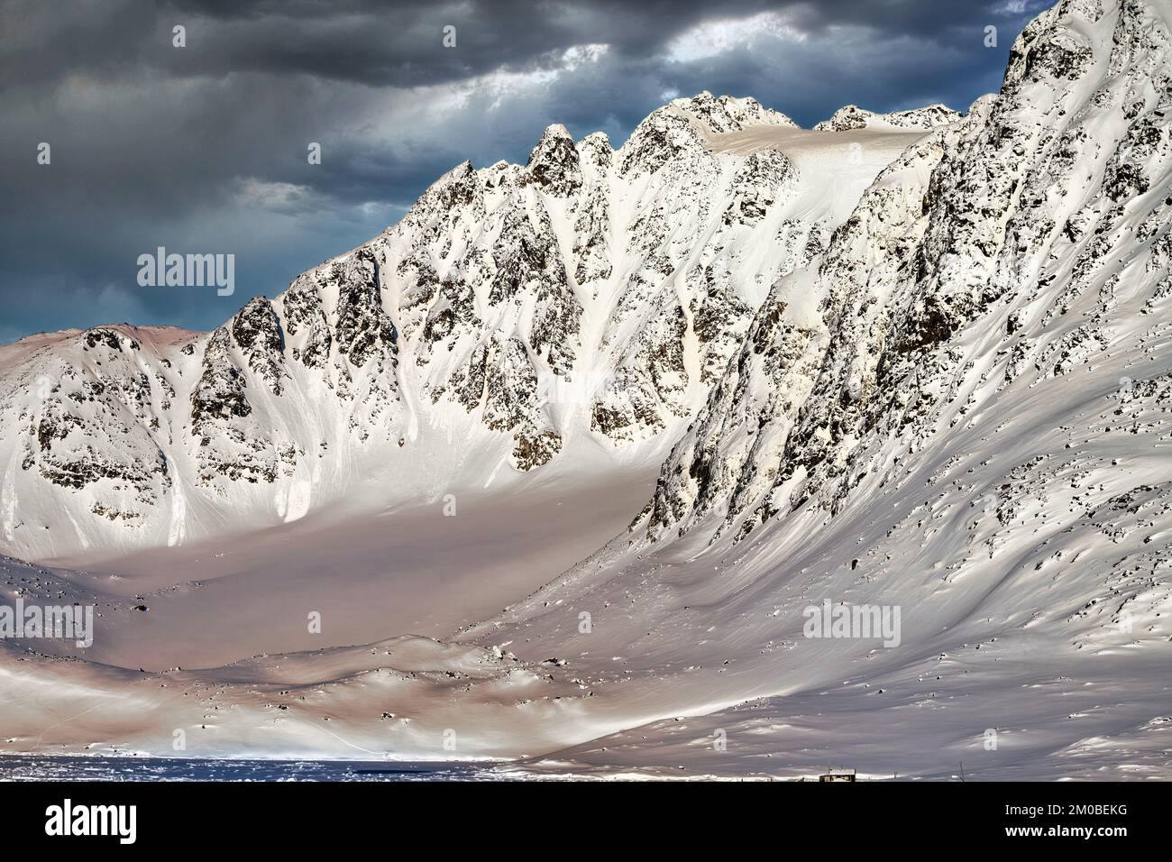 A mesmerizing view of jagged snowy mountains under dark clouds Stock ...