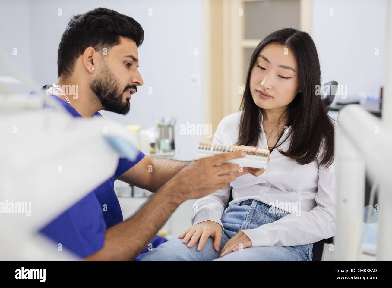 Tooth teeth tone palette. Confident bearded male cosmetologist orthodontist dentist choosing ...