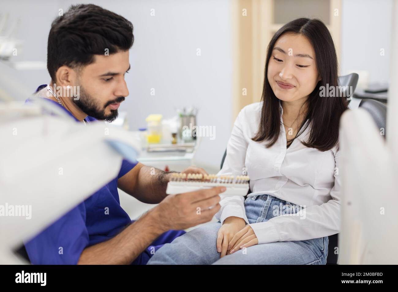 Tooth teeth tone palette. Confident bearded male cosmetologist orthodontist dentist choosing ...