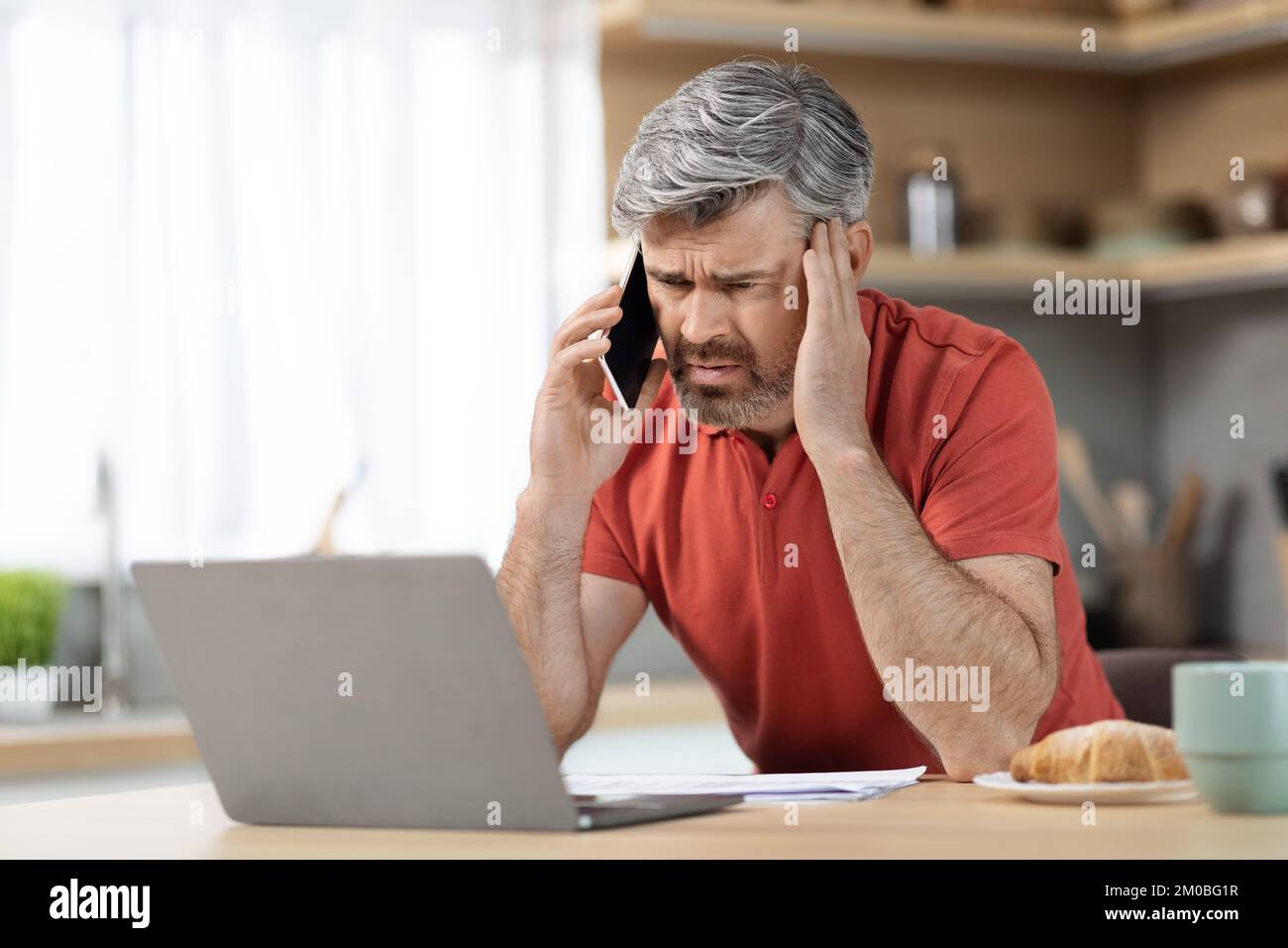 Stressed middle aged businessman working from home, having phone call ...