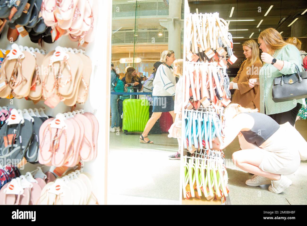 Travellers with suitcases are reflected in a mirror as people look at ...