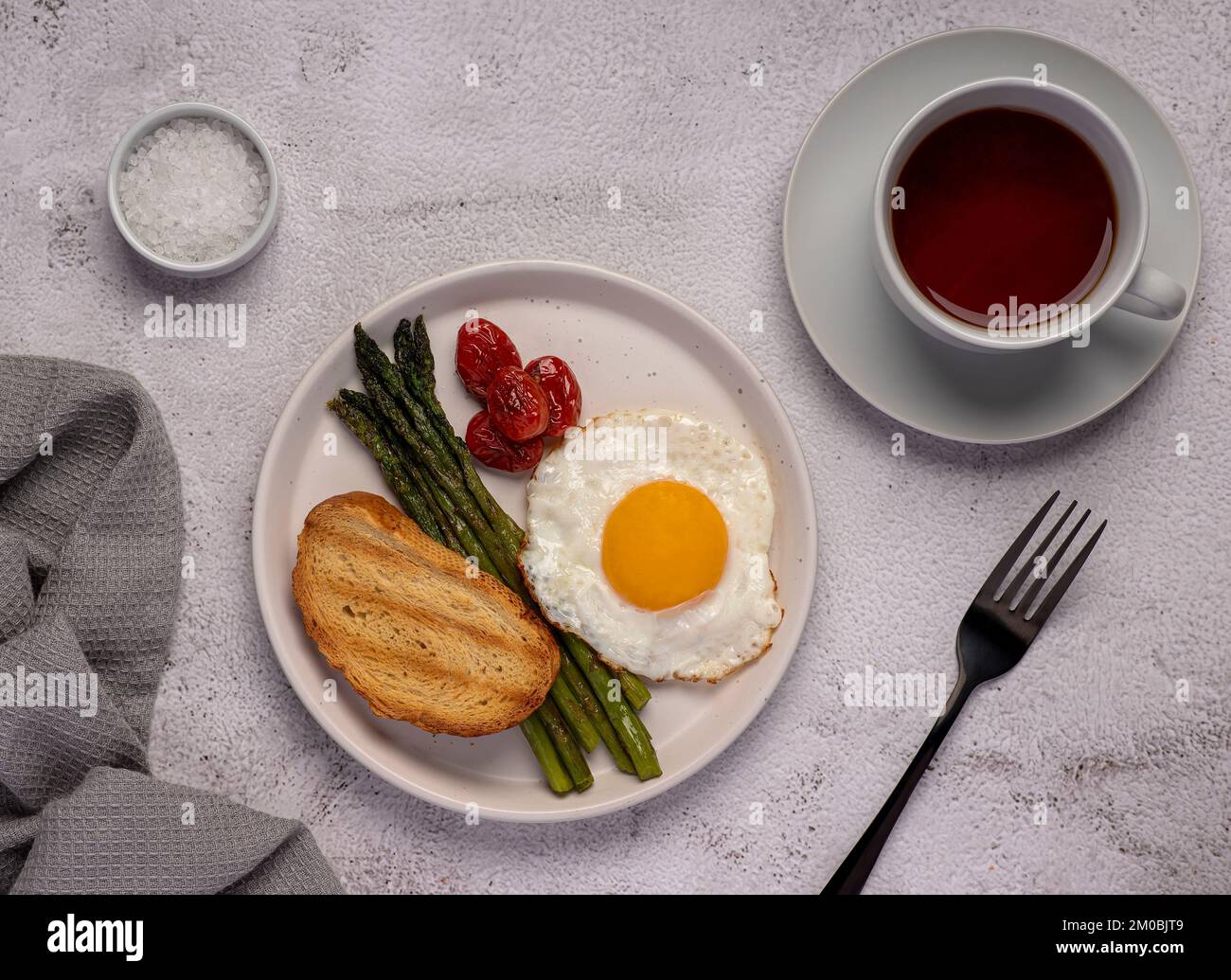 Food photography of fried egg, tomato, asparagus, toast, tea, salt ...