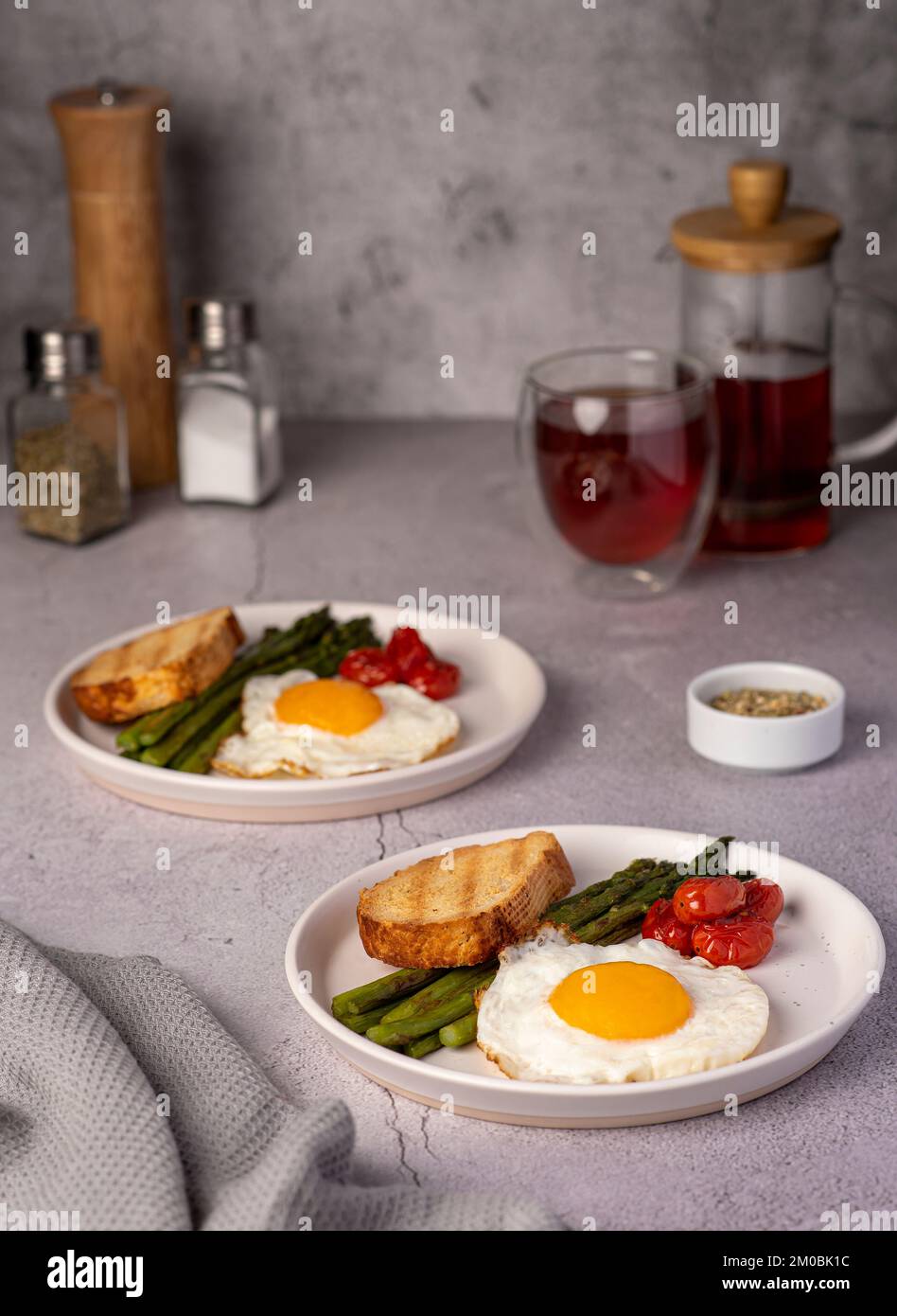 Food photography of fried egg, tomato, asparagus, toast, tea, salt ...