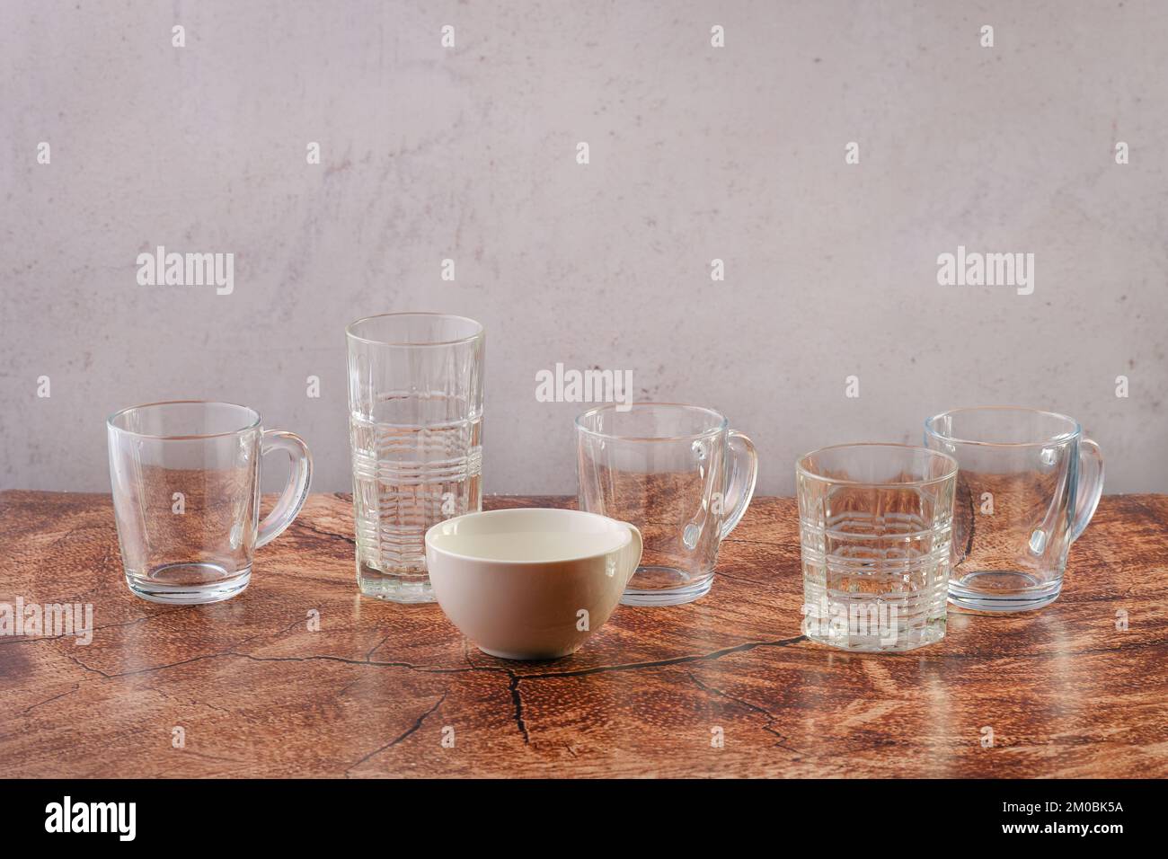 Empty glasses and cups of different forms and shapes on wooden tabletop ...