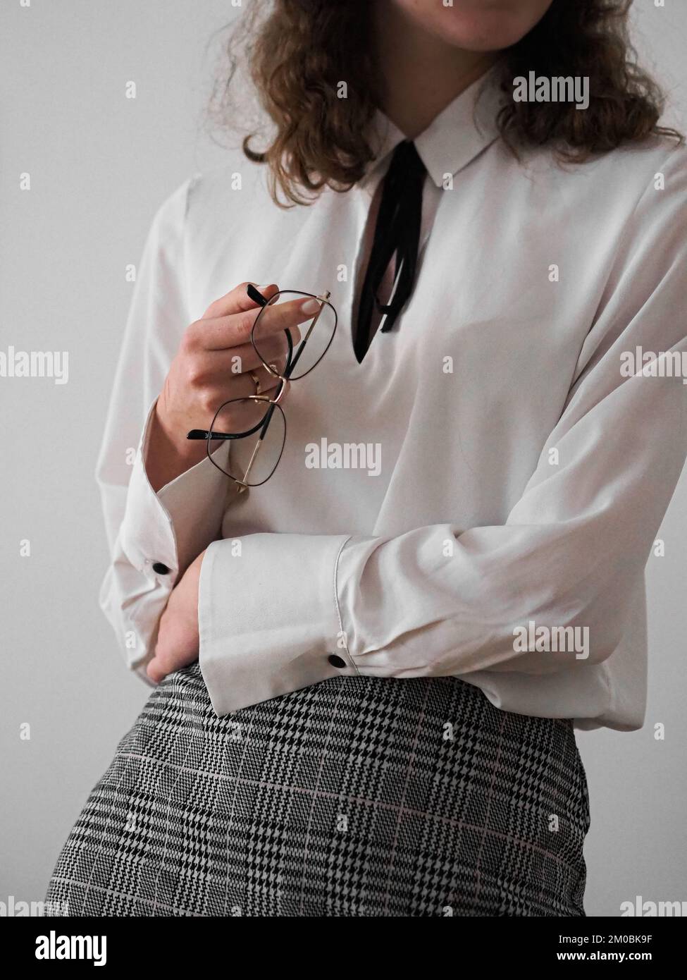 A vertical shot of a young woman's hands holding sunglasses and wearing ...