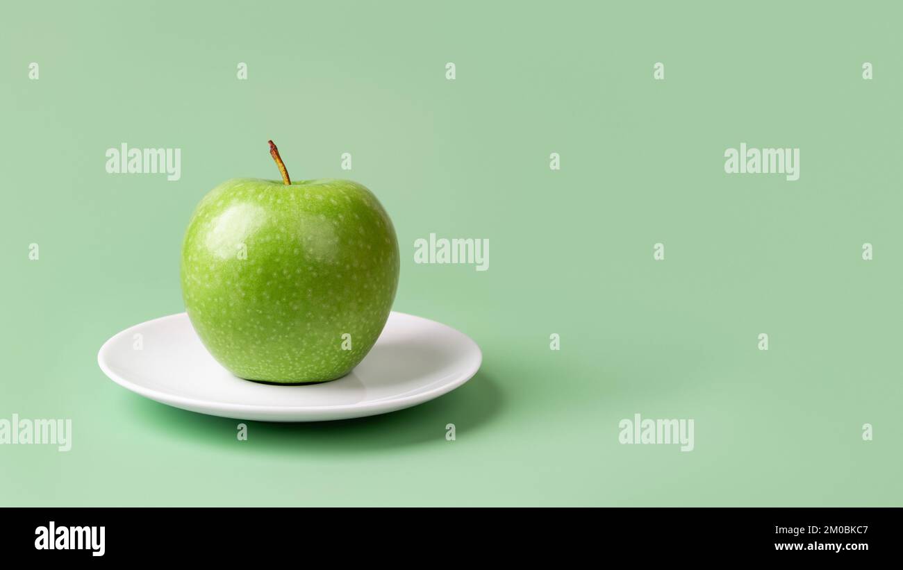 Fresh green apple on a white saucer over pastel green background ...
