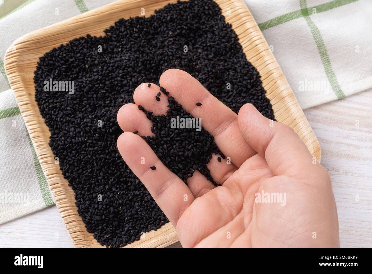 Pinch of black cumin seeds on a woman hand palm closeup. Using organic ...