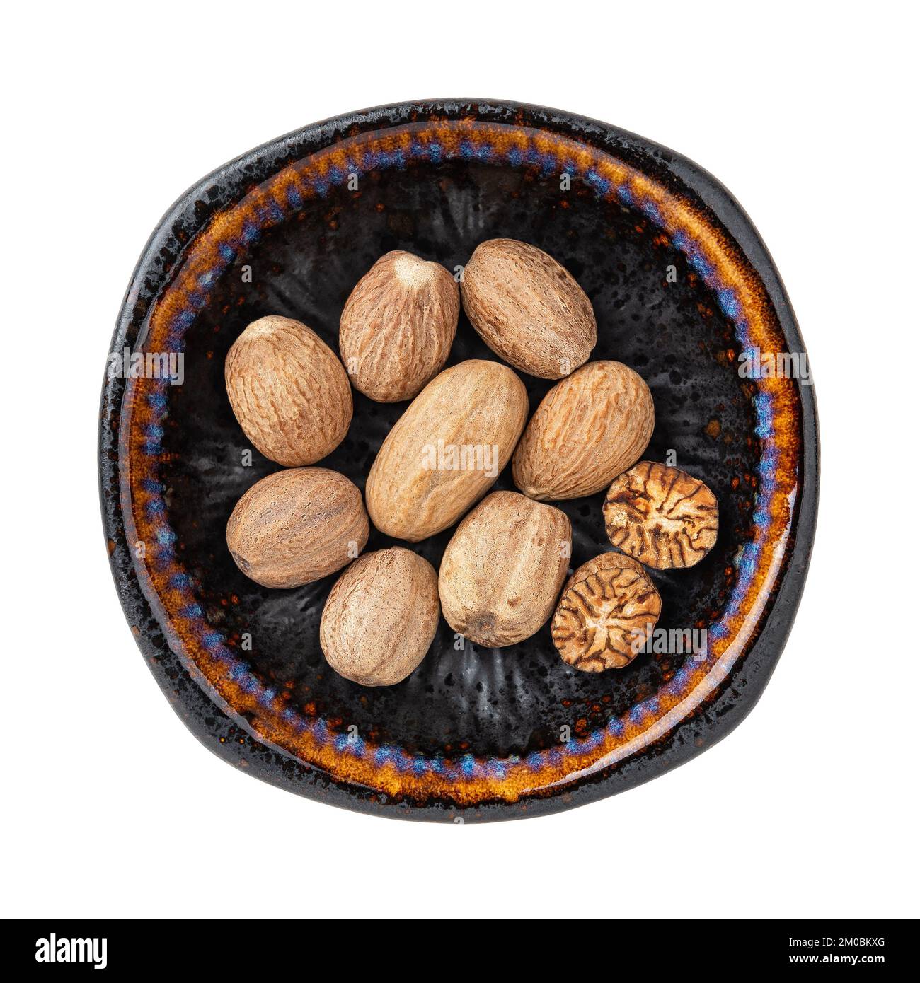Whole and halved nutmeg seeds on a black plate cutout. Nutmeg seeds on ...