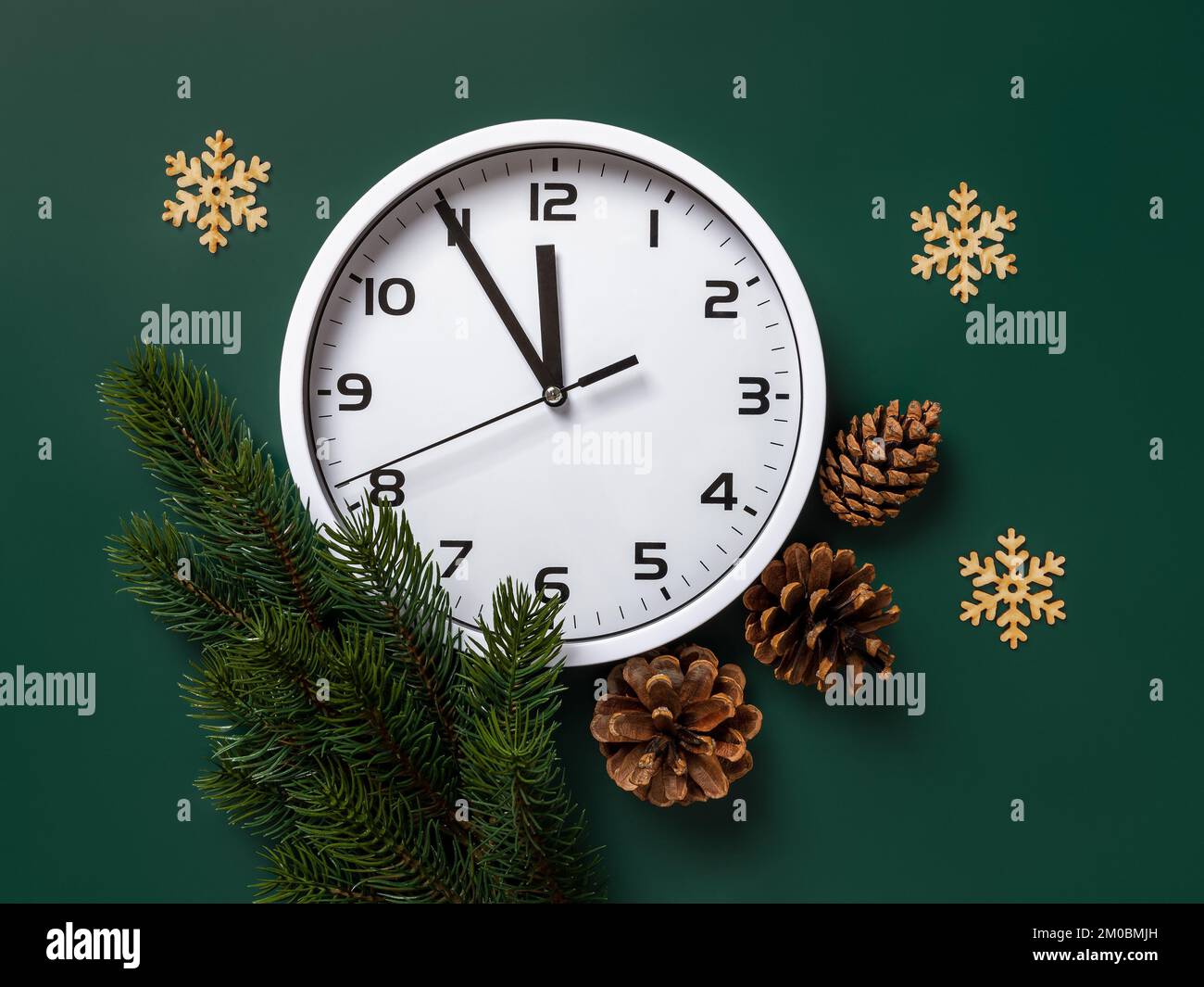 White clock and fir branch over green background. Office style clock ...