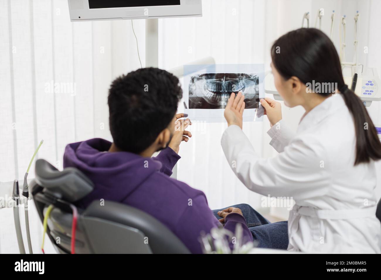 Back view of young attractive man visiting dentist, sitting in dental ...