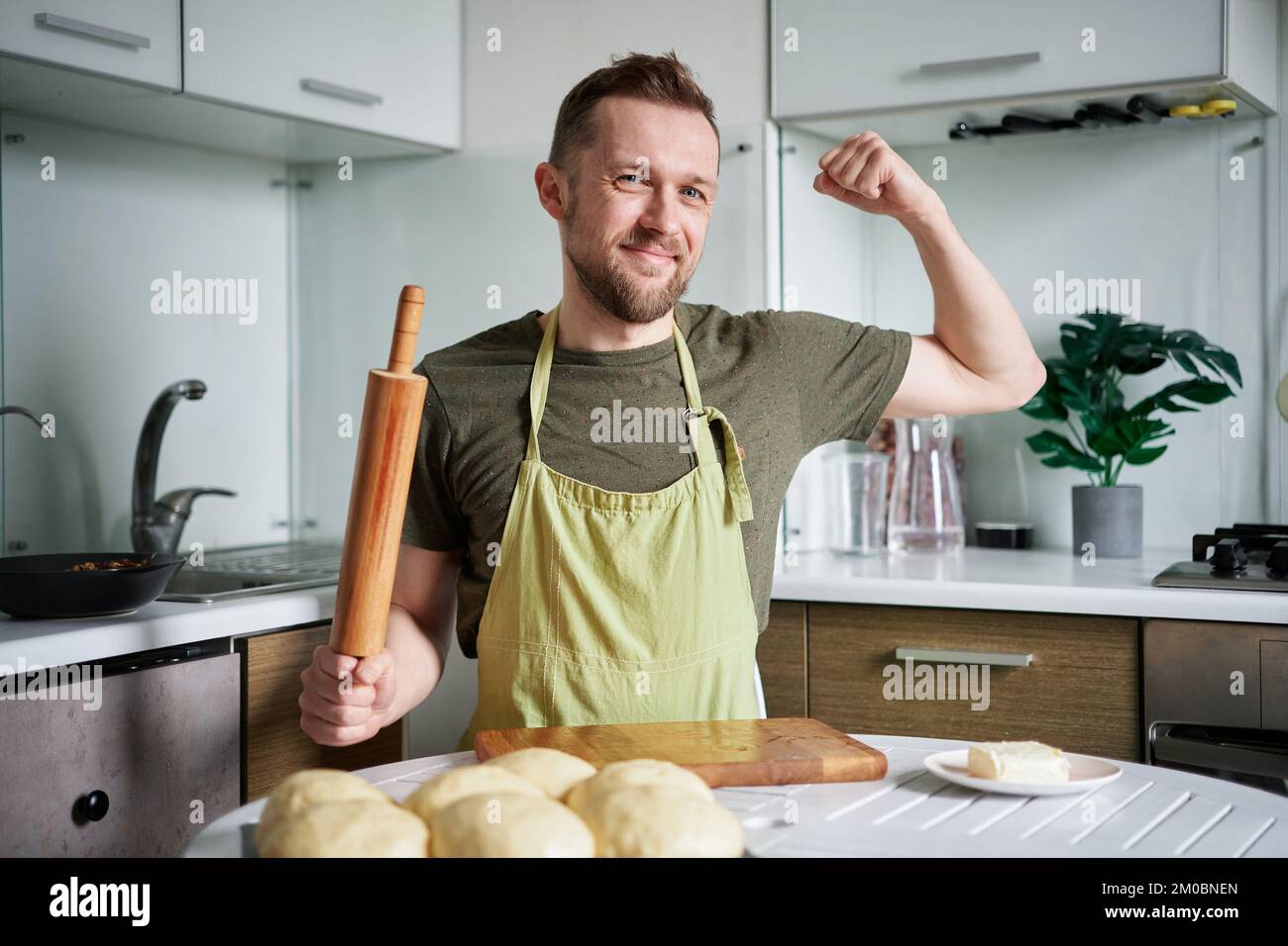 Portrait of caucasian baker man in green apron uniform smiling looking ...
