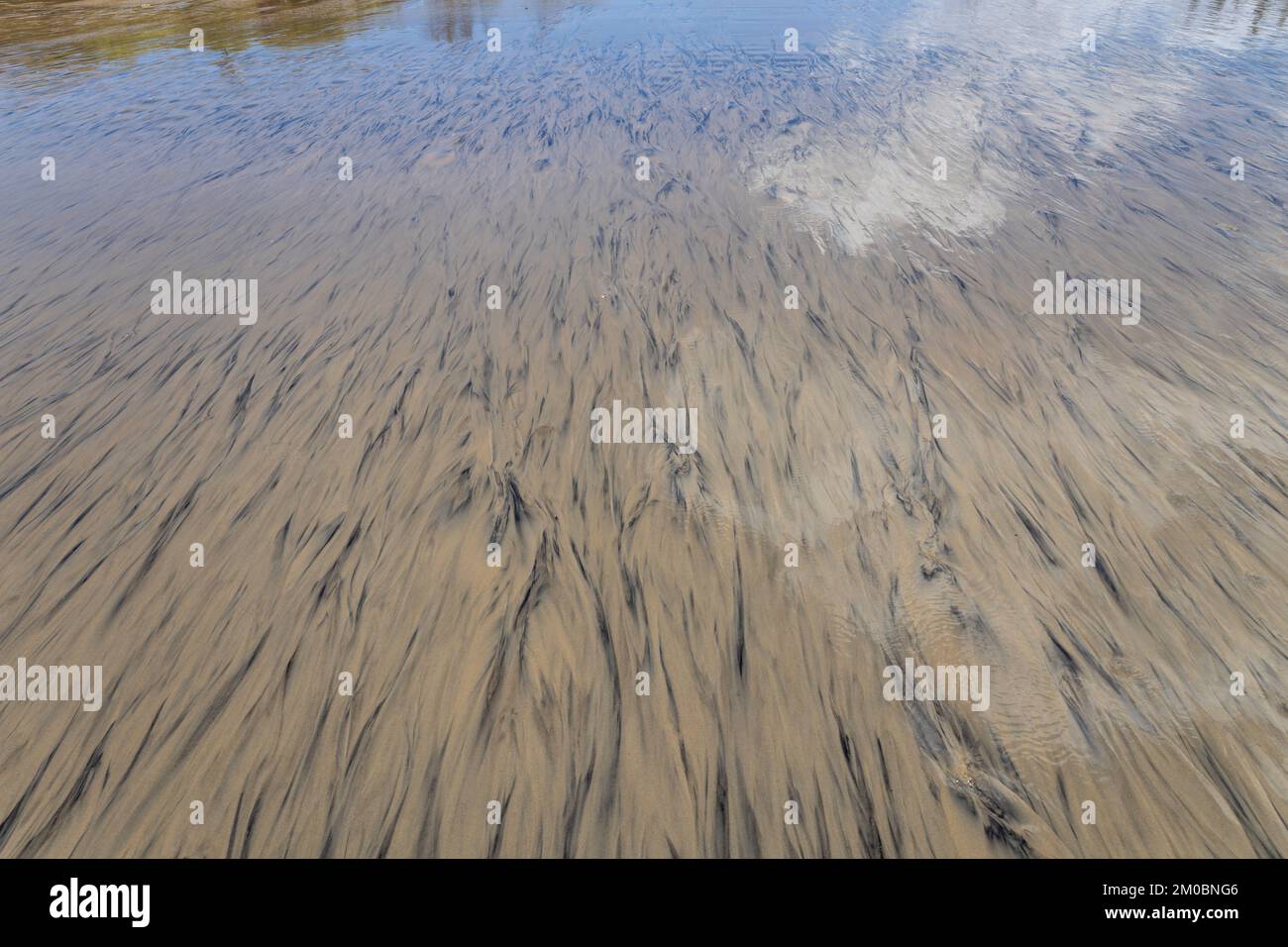 Abstract wavy patterns of different colors formed by sand and water ...