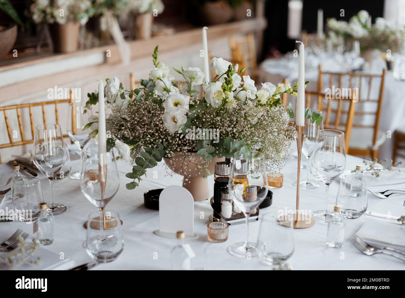 A beautifully decorated table with white flowers bouquet, glasses and ...