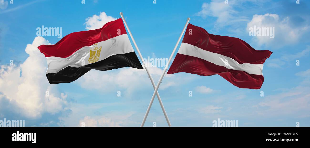 two crossed flags latvia and Egypt waving in wind at cloudy sky ...