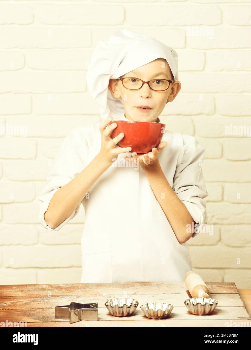 young boy small cute cook chef in white uniform and hat on funny face ...