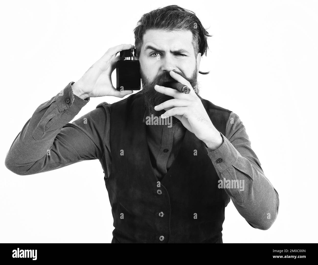 bearded man smoking cigar with serious face, holding perfume Stock ...