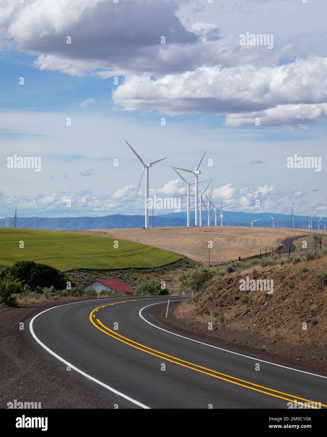 A vertical shot of the countryside road passing by the Wind Turbine ...