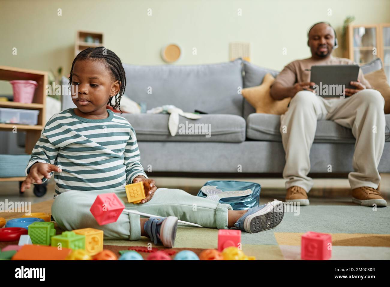 Full length portrait of cute black baby playing with toys on floor ...