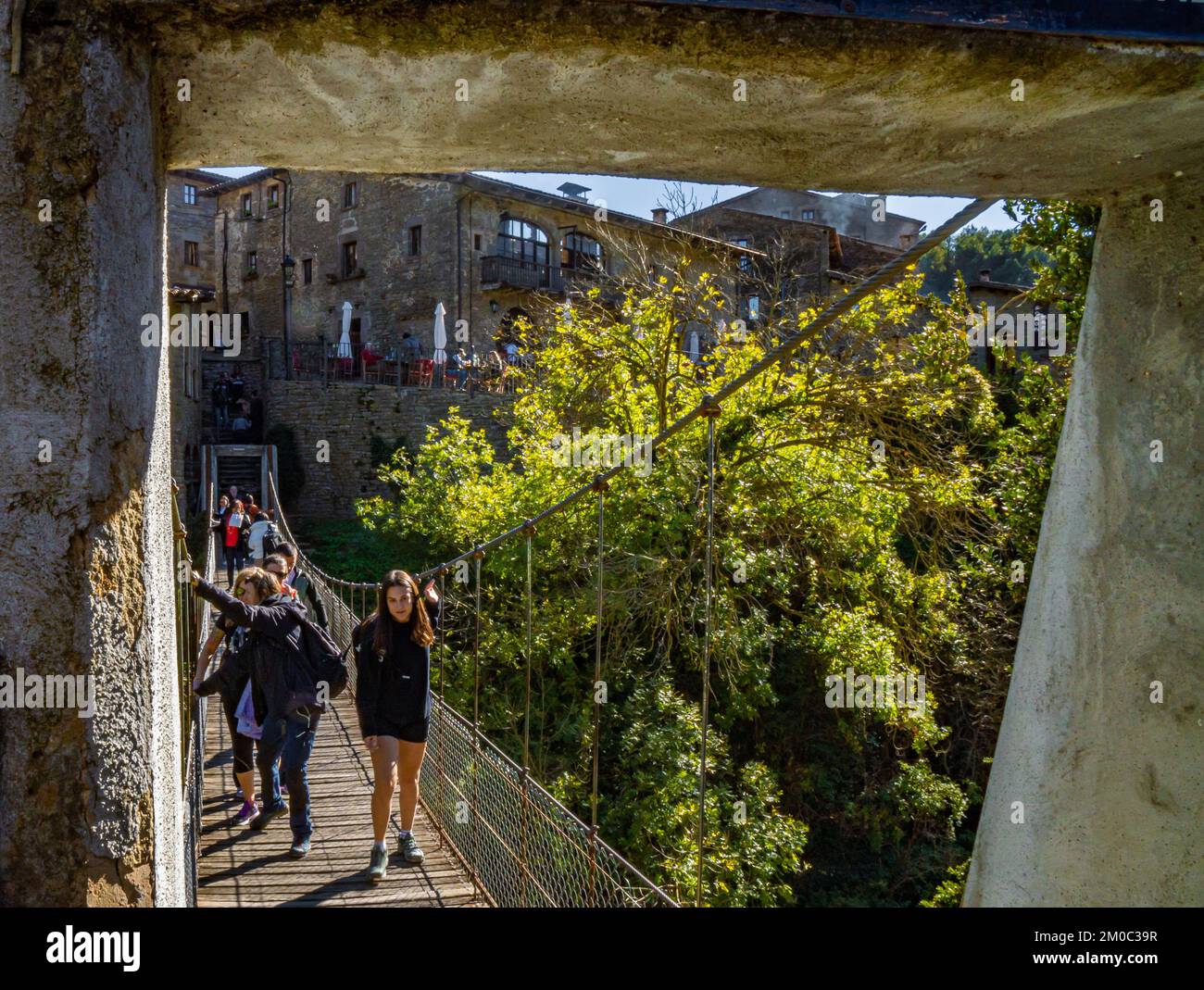 People crossing the suspension bridge of Rupit and old houses in the ...