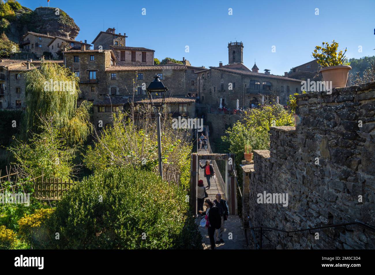 People crossing the suspension bridge of Rupit and old houses in the ...