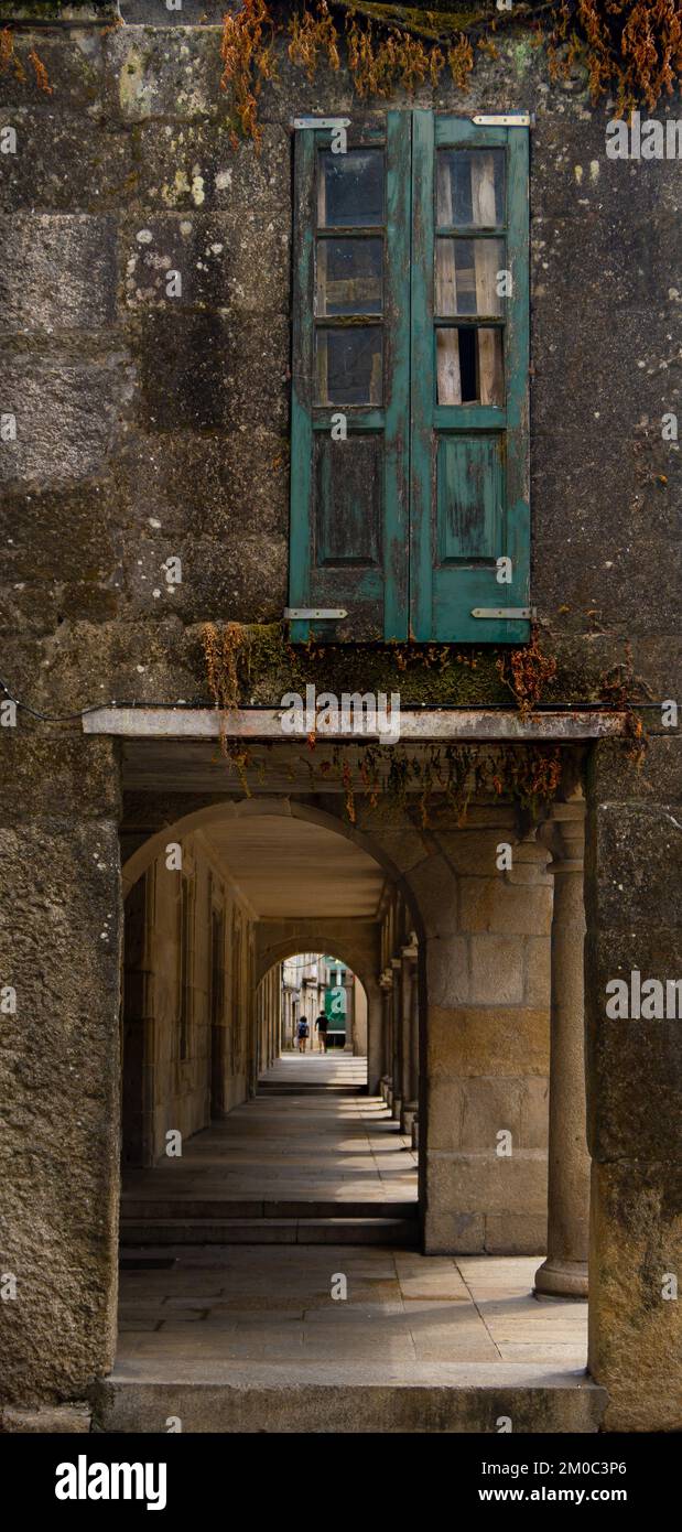 Old green wooden window and below street passage through columns of the ...