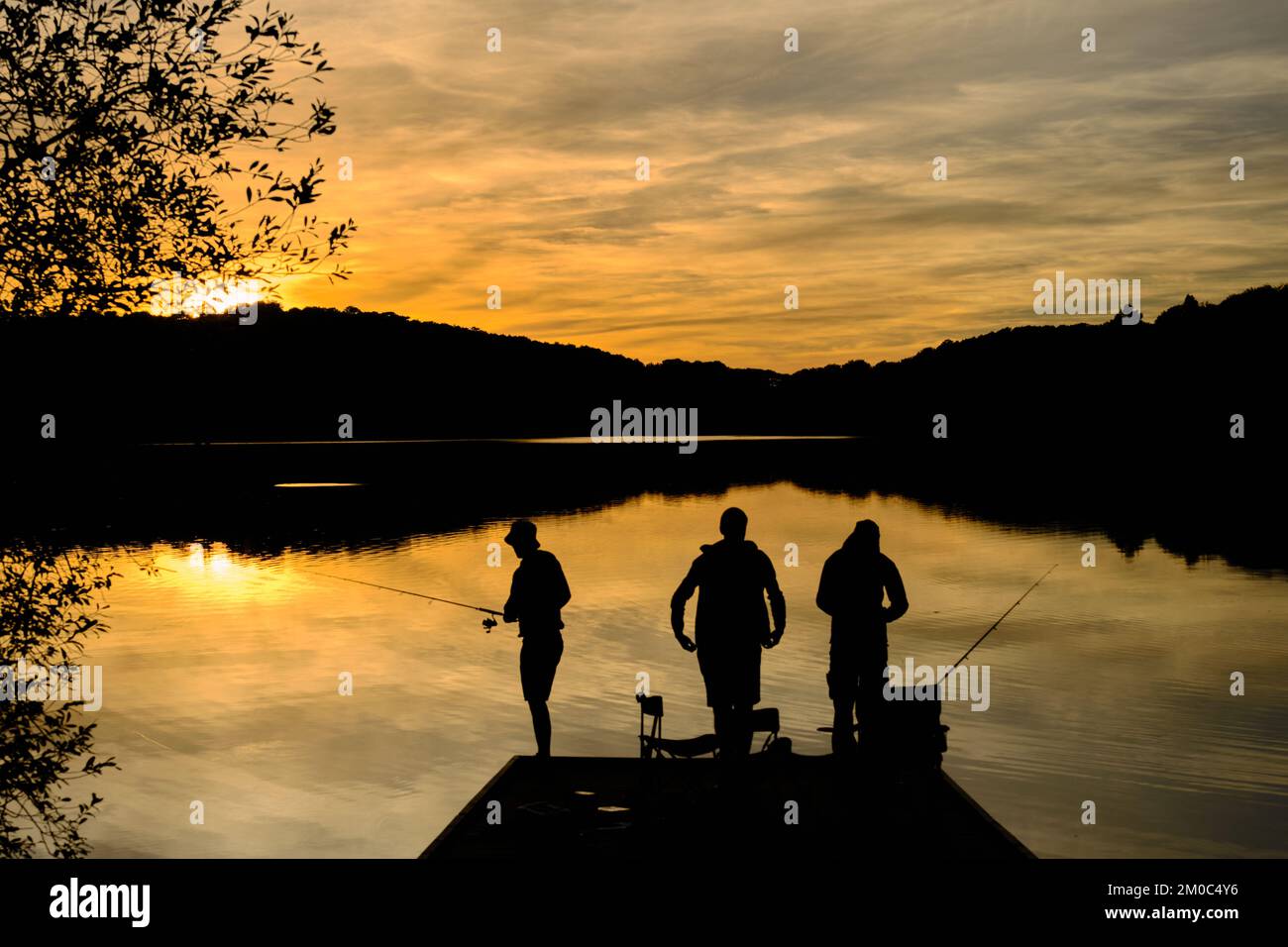 landscape of some friends fishing in a lake while watching the sunset ...