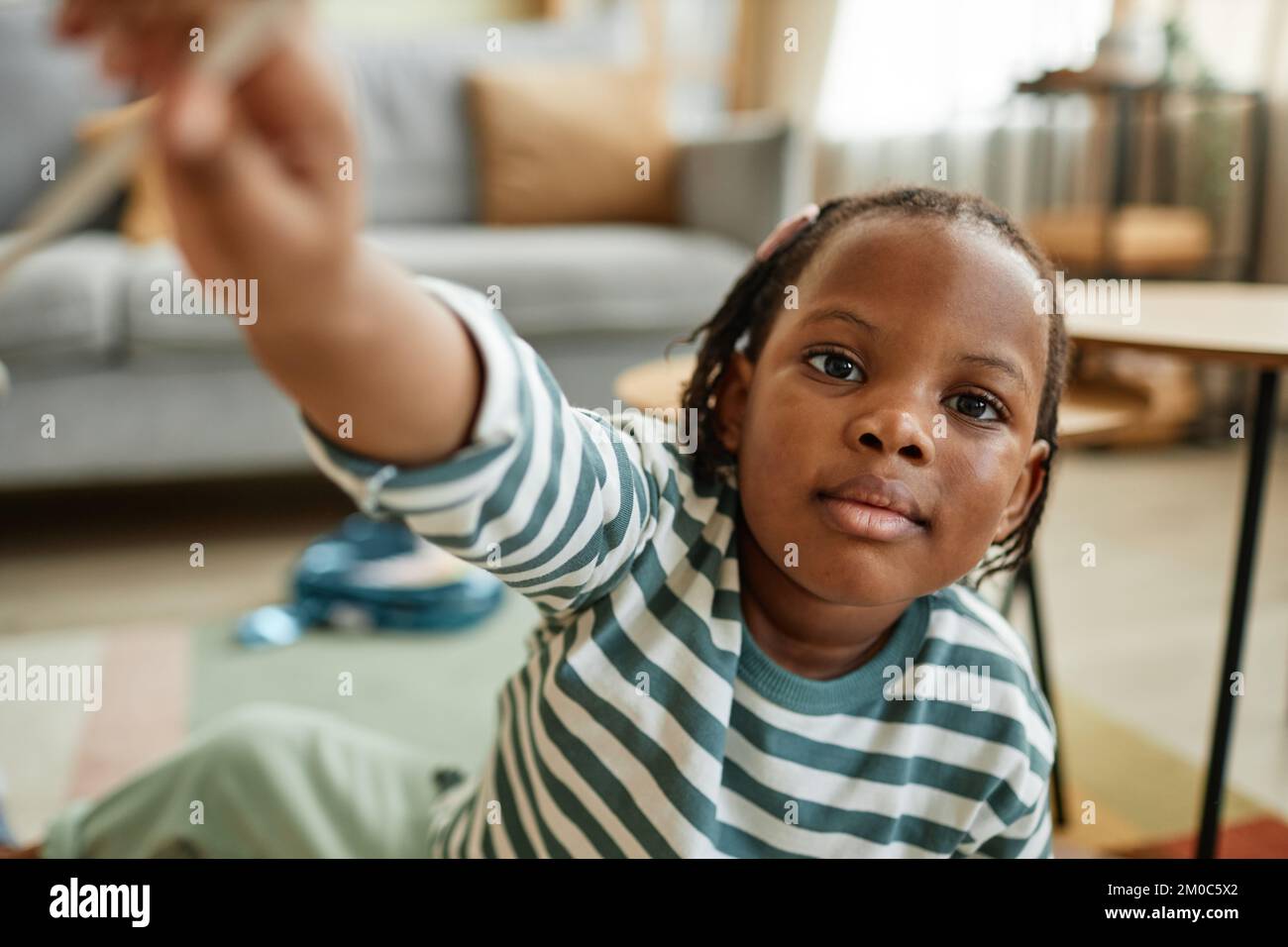 Portrait of cute black baby reaching for camera close up in cozy home ...