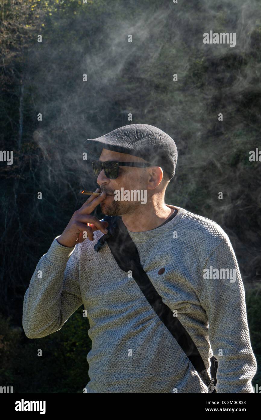 Modern man and artist in a bohemian cap with sunglasses smoking his ...