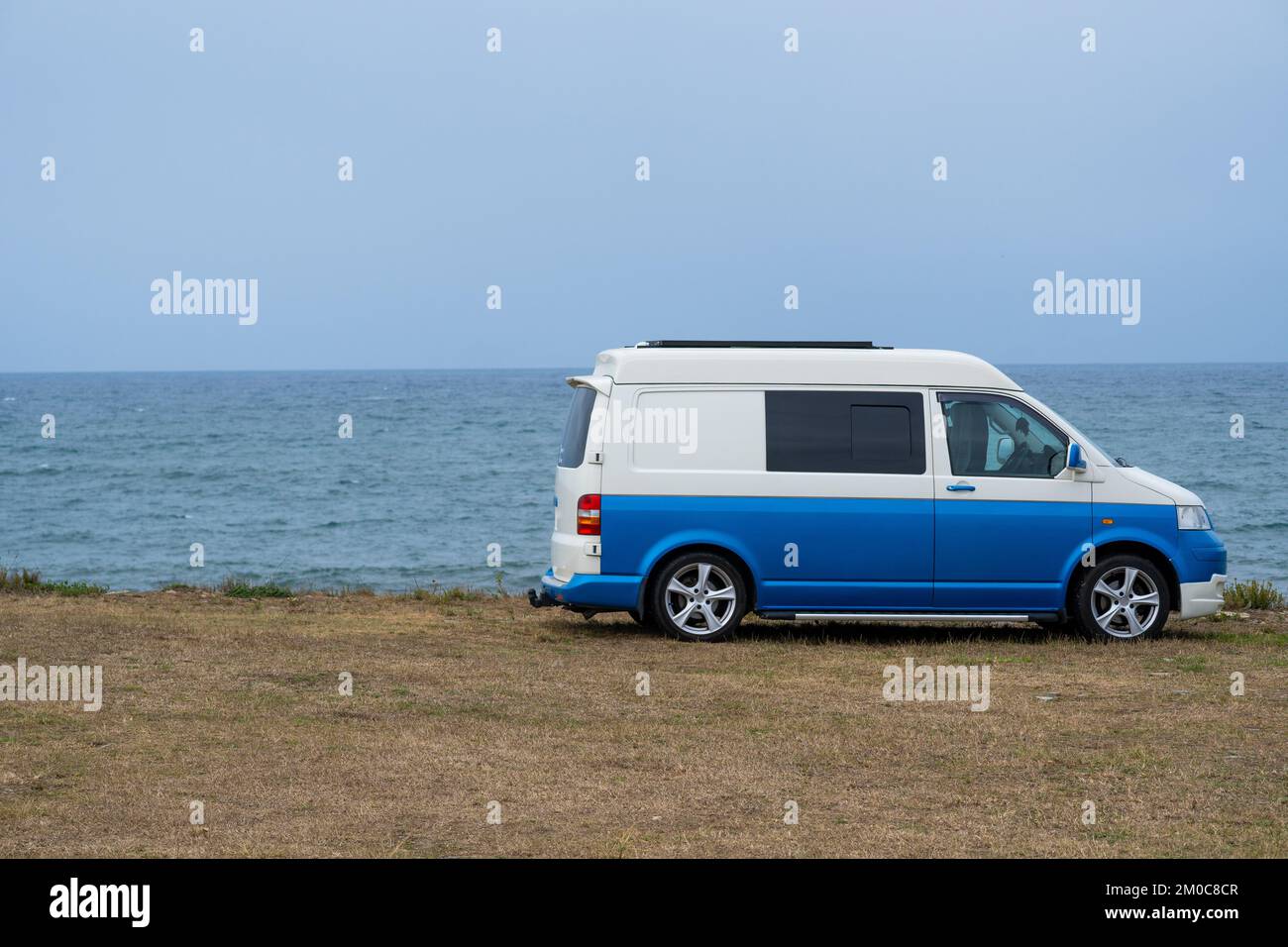 Vintage blue motorhome parked on a grassy plain with the Atlantic Ocean ...