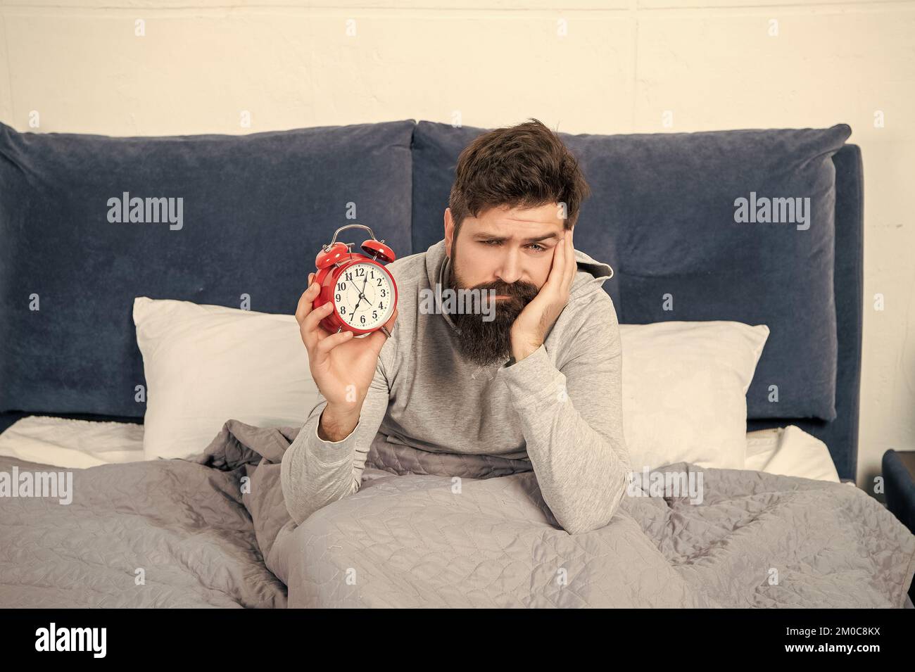 Sleepy guy holding alarm clock being in bed in morning, time Stock ...