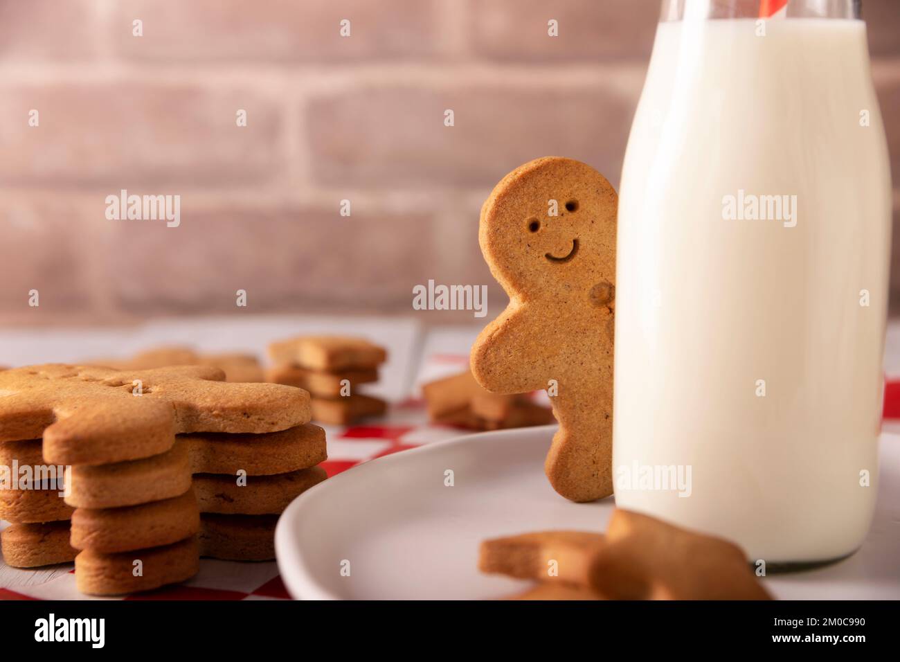 Homemade smiling gingerbread man cookie peeking out from behind a milk ...