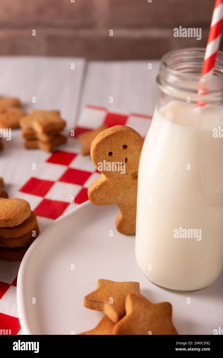 Homemade smiling gingerbread man cookie peeking out from behind a milk ...