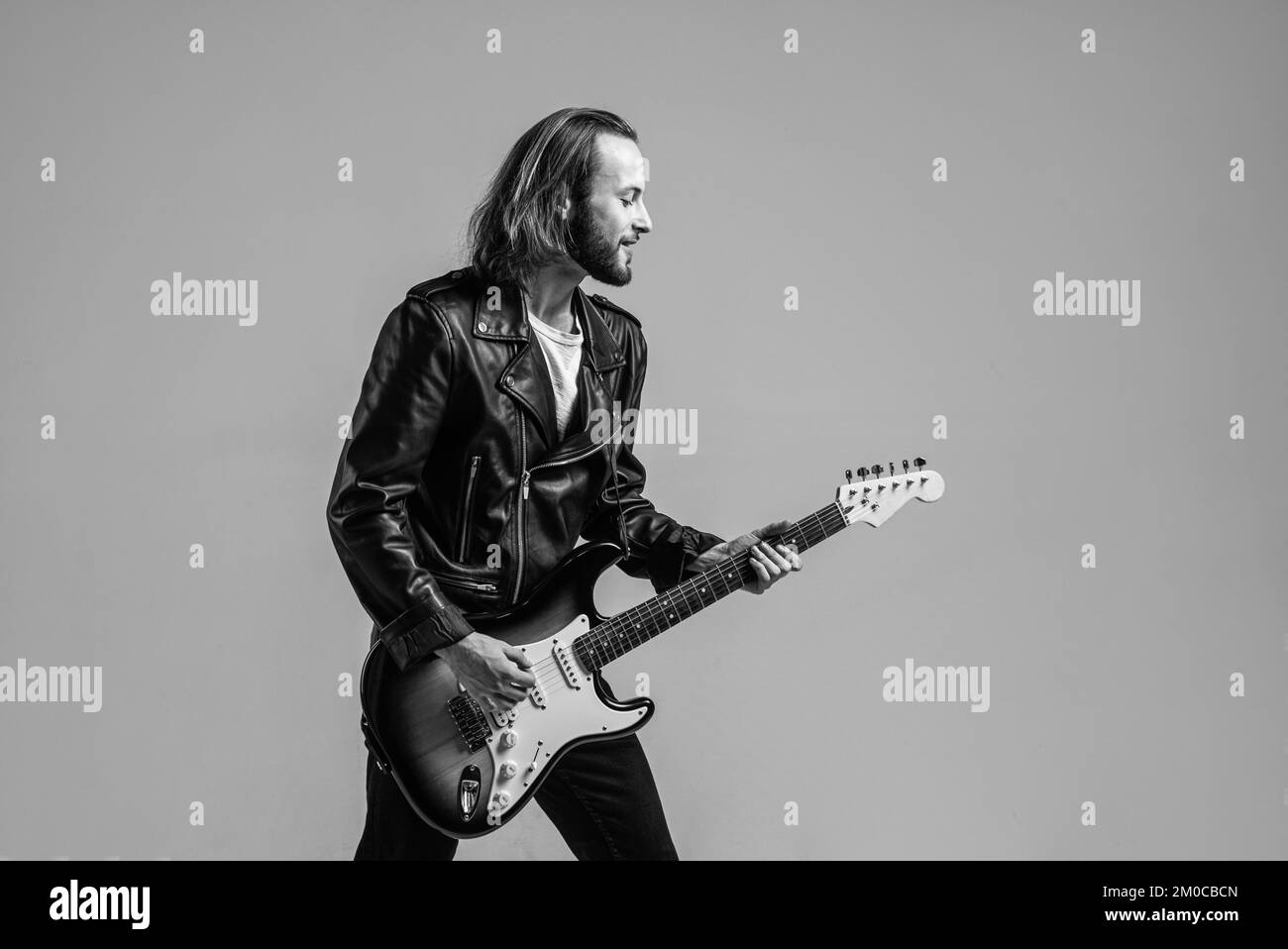 bearded rock musician playing electric guitar in leather jacket ...