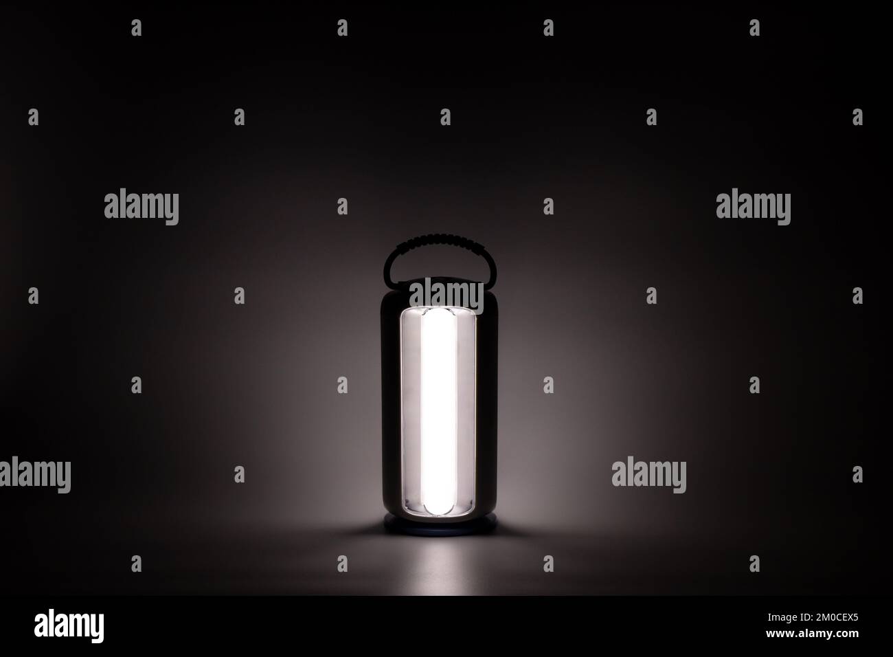 Hand-held LED lamp shines in the dark on a white background ,light and ...