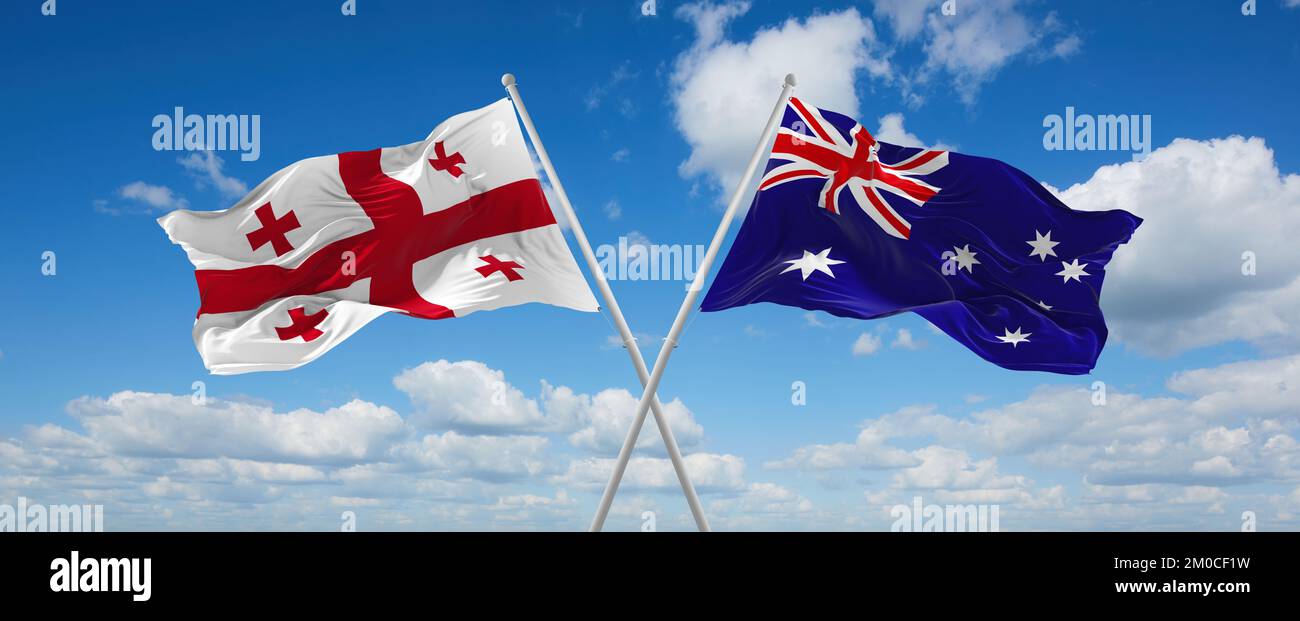 two crossed flags Australia and Georgia waving in wind at cloudy sky ...