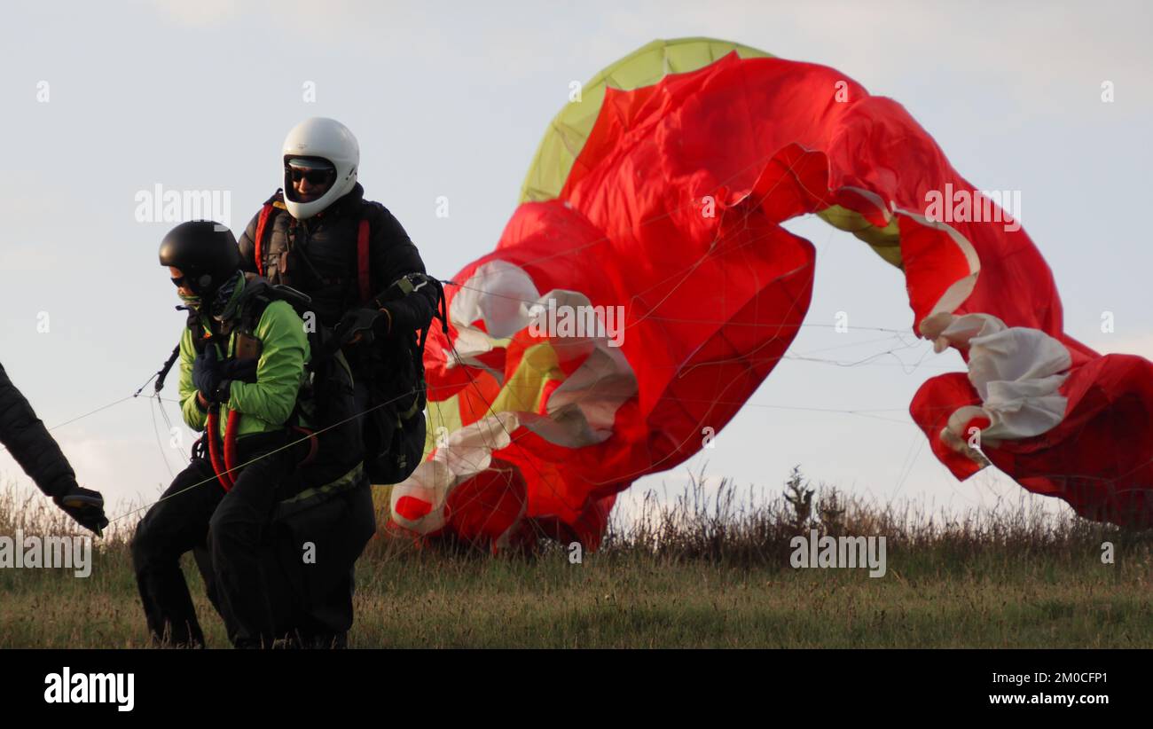 A group of people landing after paragliding with the cloudy sky in the ...